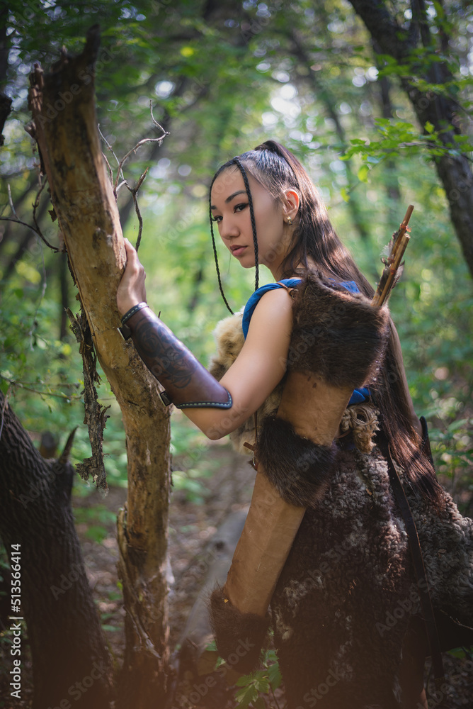 Beautiful asian woman an archer with the bow is hunting in the forest ...
