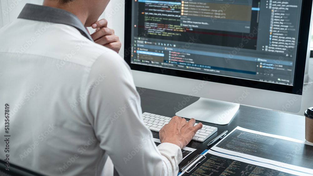 Male programmer working on website project in software development on the desktop computer and ...