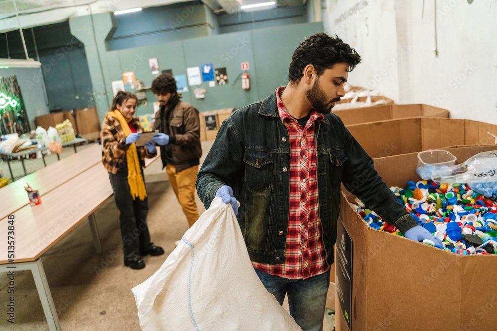 Foto de Indian man sorting plastic bottle caps at garbage recycling ...