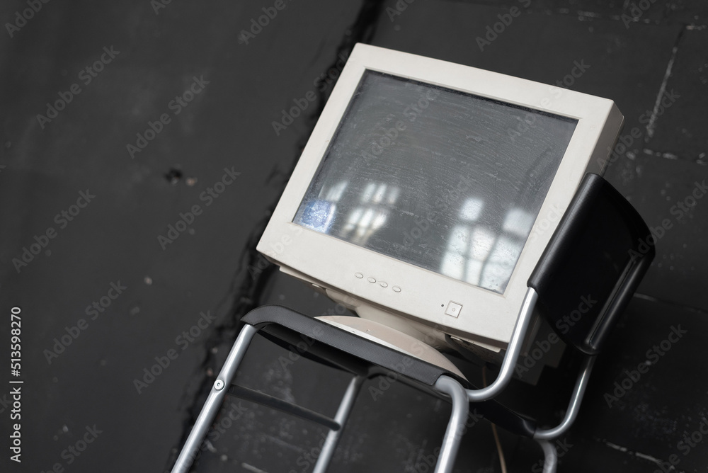 Old computer monitor on the chair on the black wall background. Stock ...