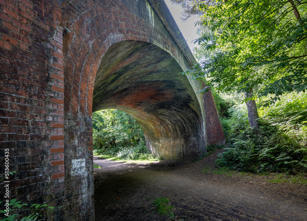 Bridge over a disused railway showing curved arches and brickwork lit ...