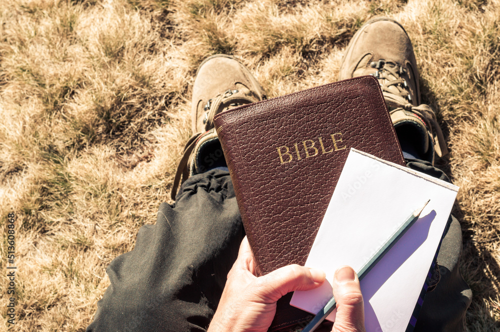 Outdoor Bible study during mountain hike. Female hands holding a Bible ...
