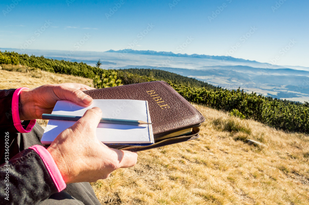 Outdoor Bible study during mountain hike. Female hands holding a Bible ...