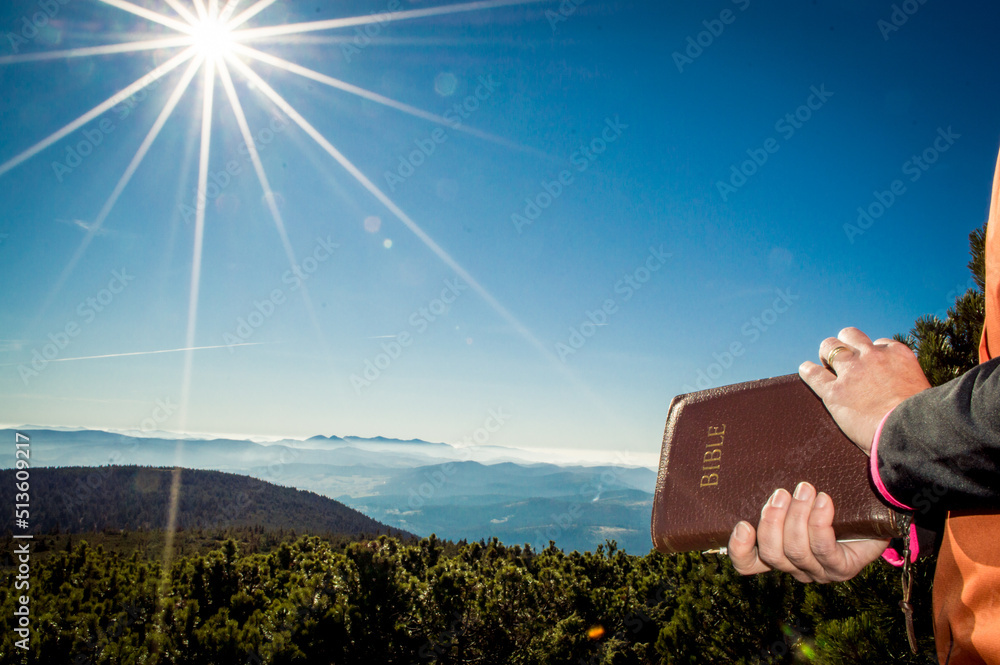 Outdoor Bible study during mountain hike. Female hands holding a Bible ...