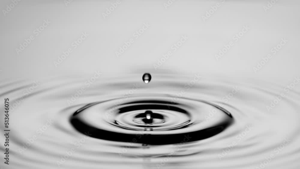 A single drop of water falling into a pool of water in slow motion ...