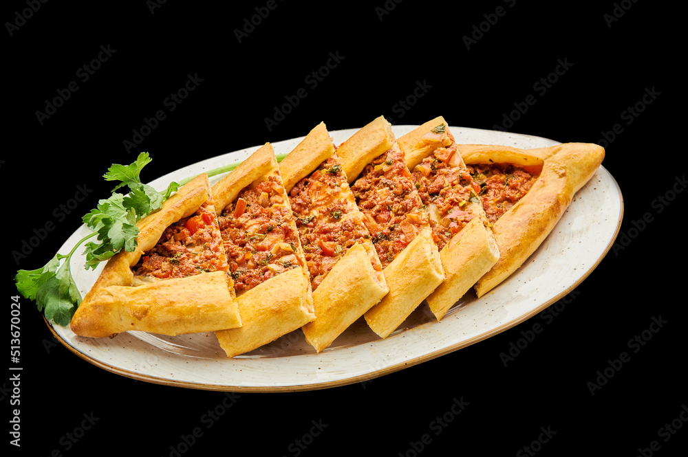 turkish pizza pide with minced meat lies on a plate on a black isolated ...