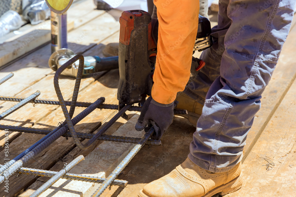 Construction worker use rebar tying tools to secure steel bars with ...
