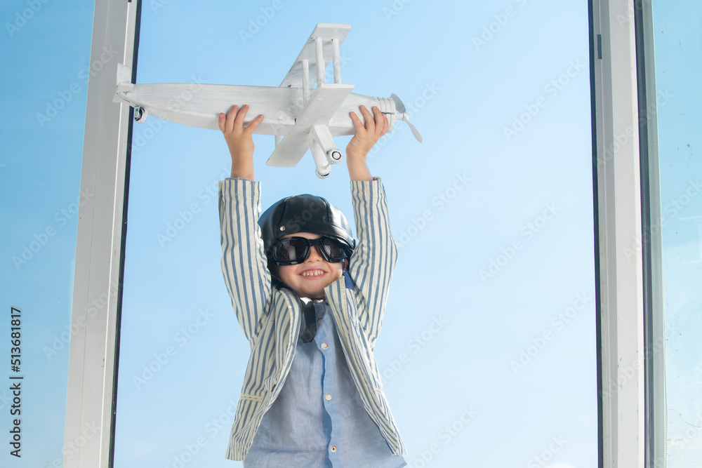 Child boy with pilot goggles and helmet playing with wooden toy ...