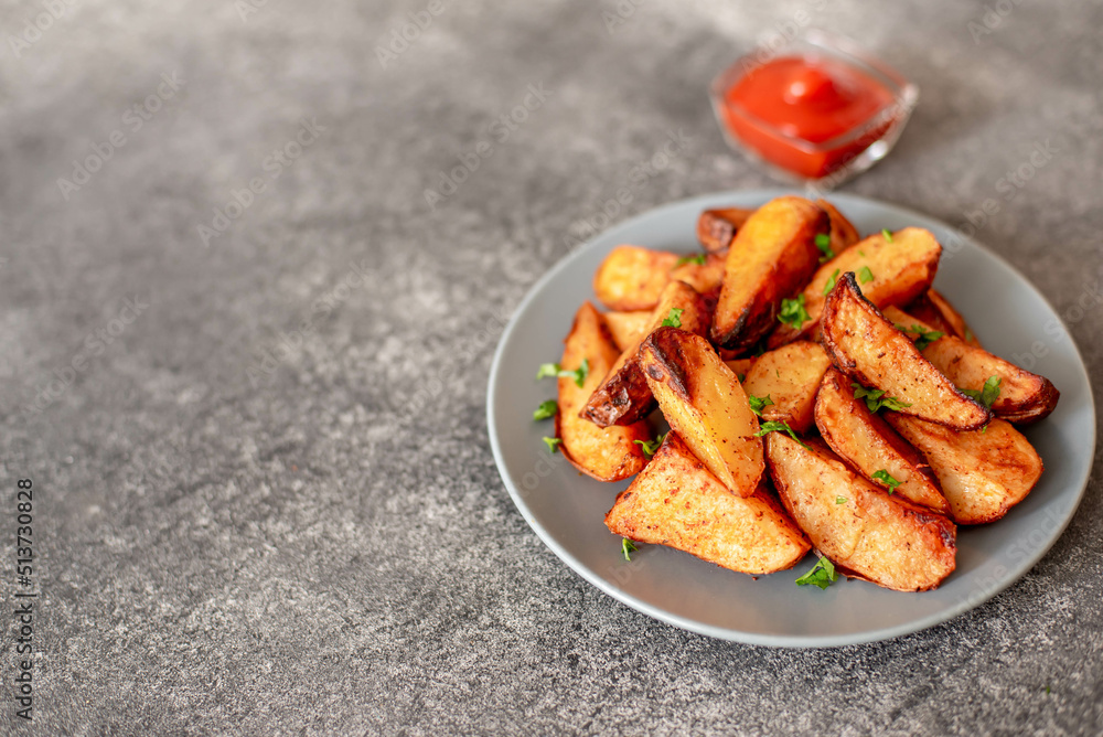 Baked potato wedges with herbs and sauce on stone background - homemade ...