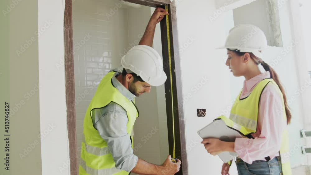 Construction workers measuring of room door using measure tape at ...