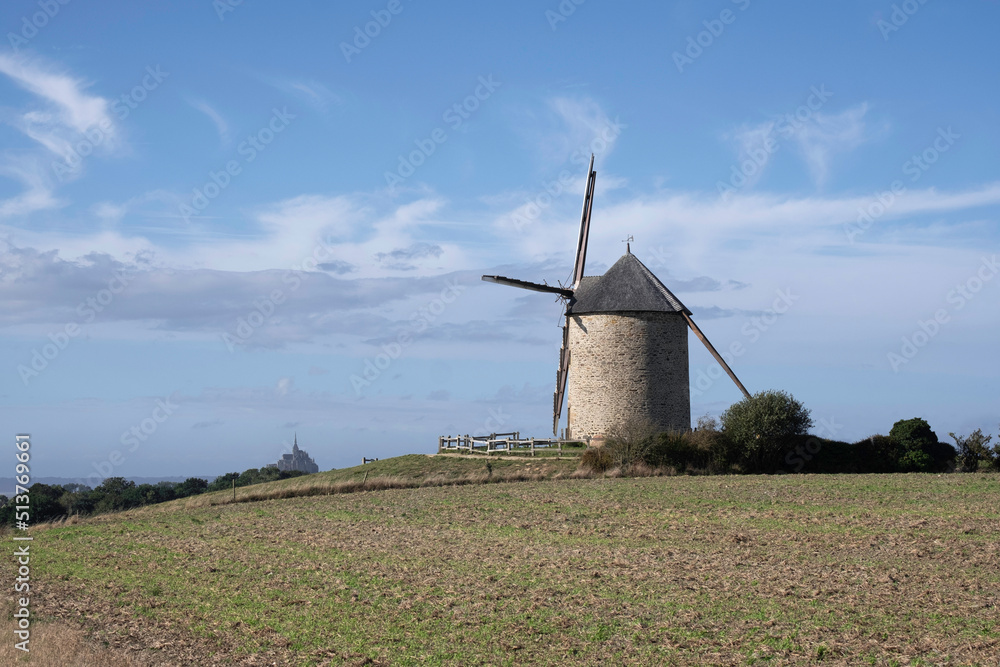 Windmill on a top of a hill with Mont Saint Michel in the backround ...