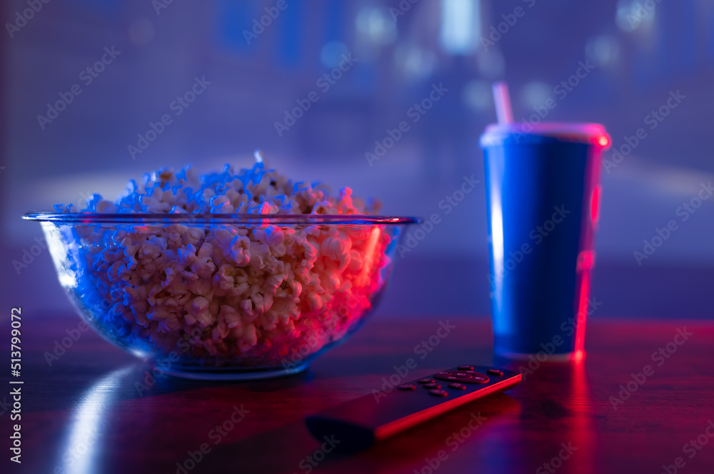 Popcorn in a transparent bowl, a drink in a plastic glass and a TV ...