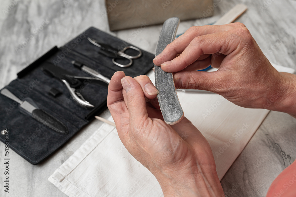 A woman aged 47-48 makes herself a manicure, takes care of her nails ...