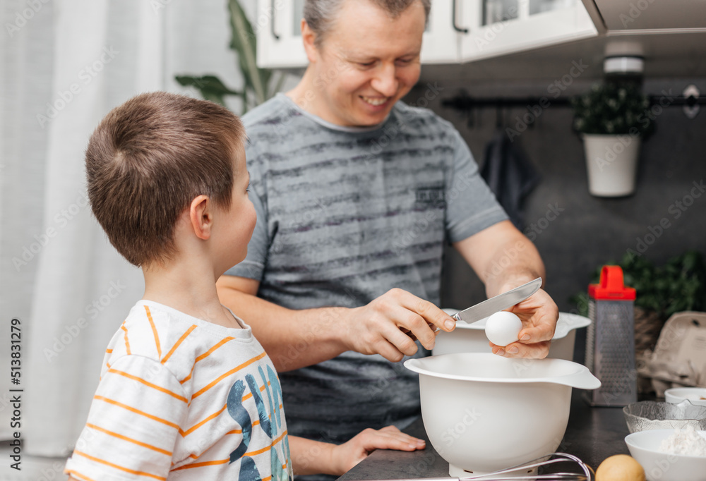 Foto de Dad and son are cooking in the kitchen. Dad teaches to break ...