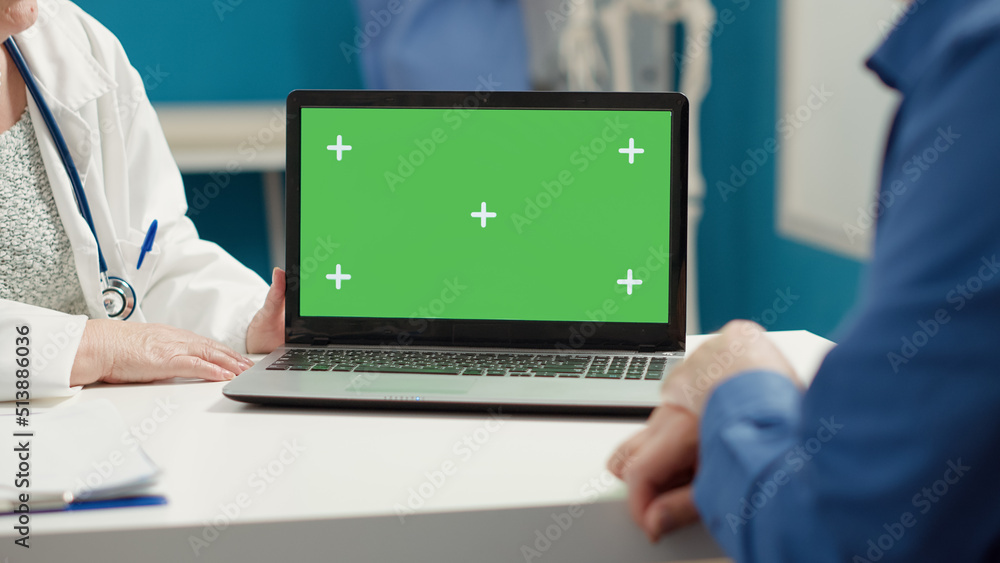 Doctor and patient looking at laptop with greenscreen display at ...