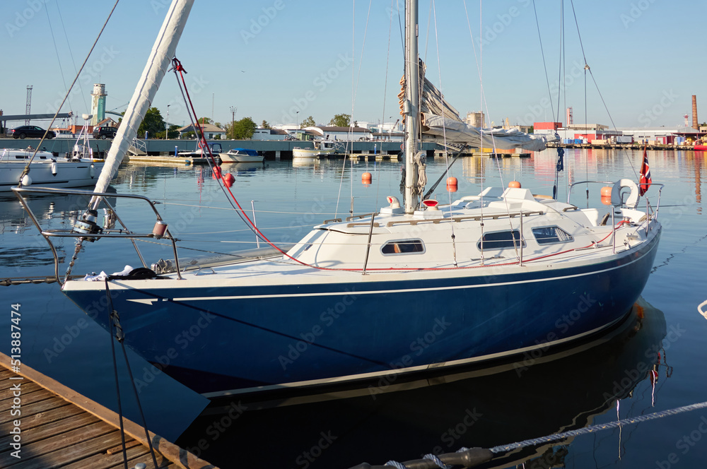 Blue sloop rigged sailboat (for rent and sale) moored to a pier in a ...