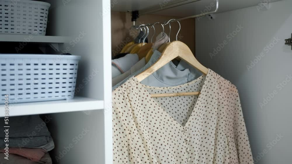Woman takes off clothes from closet in dressing room, closeup view. The ...