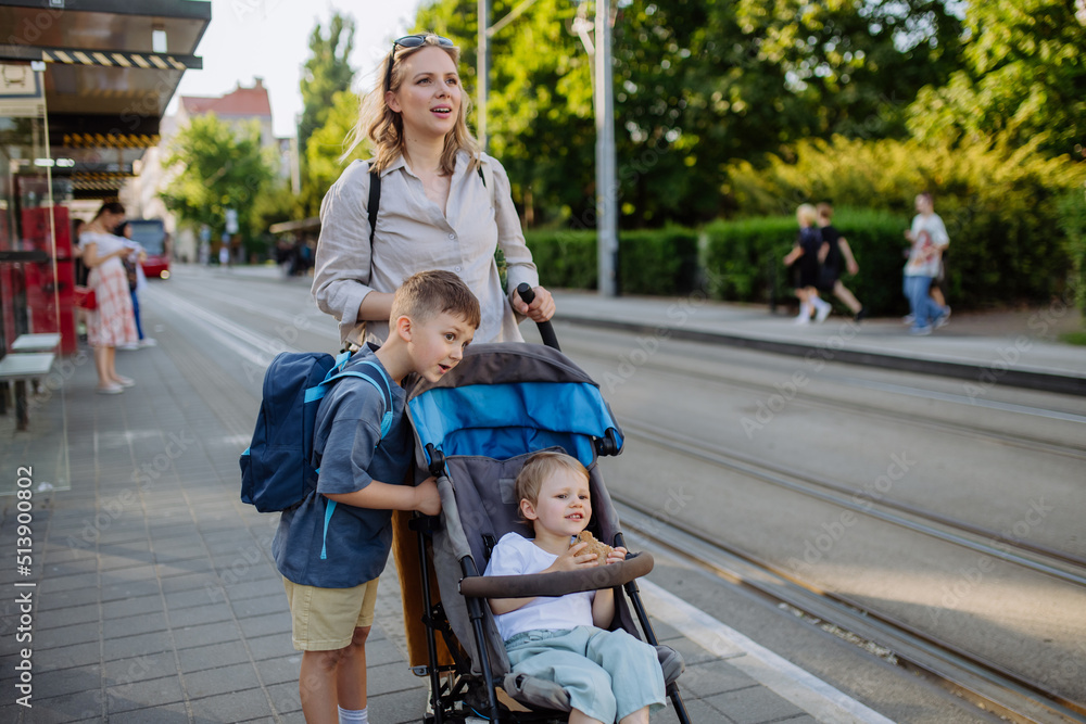 Young mother commuter with little kids on the way to school, walking on ...