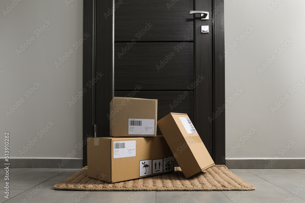 Cardboard boxes on floor mat near entrance. Parcel delivery service ...