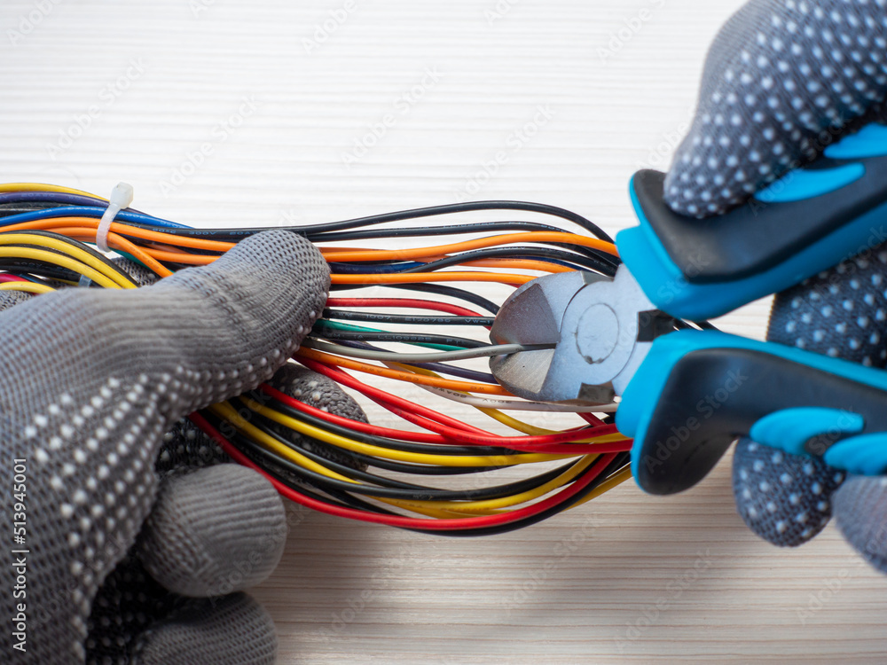 Close-up, a man with wire cutters is preparing to cut a wire among ...