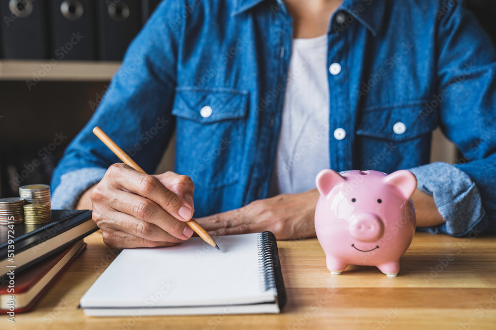 Business woman taking notes on income and expenses, saving for the ...