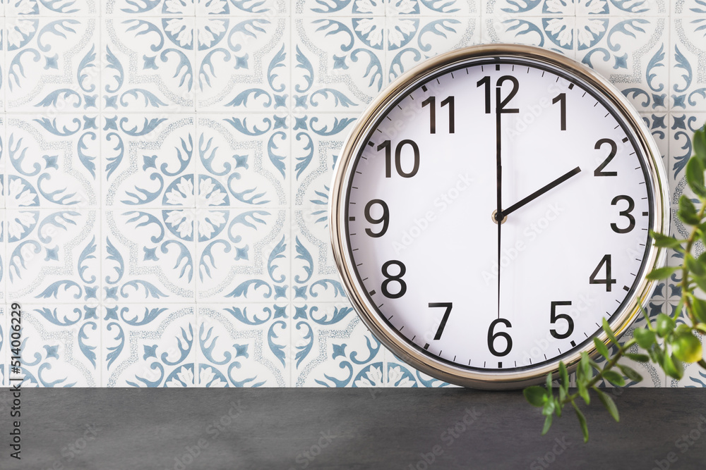 Classic, round wall clock on a marble shelf on a tile wall with home ...