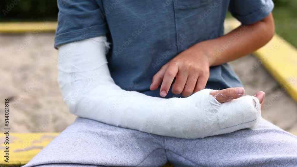 Vidéo Stock little boy with a fractured limb outdoors. a child's arm is ...