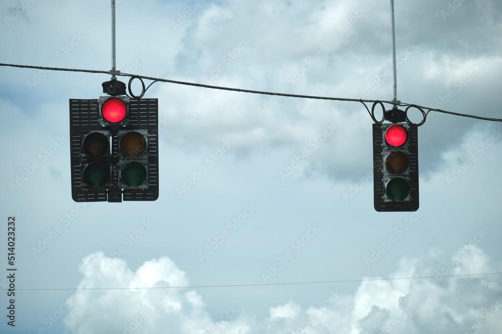 Bright red stop traffic lights high above street on blue sky background ...