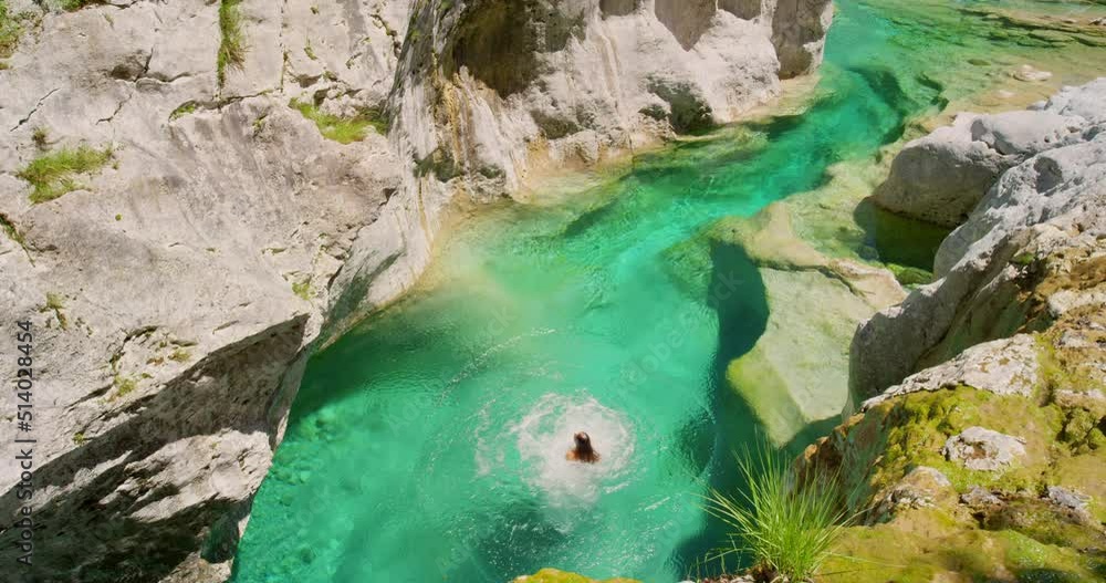 Carefree young woman jumping from a cliff to swim in a lake. Young ...