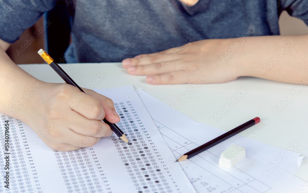 Students hand holding pencil writing selected choice on answer sheets ...