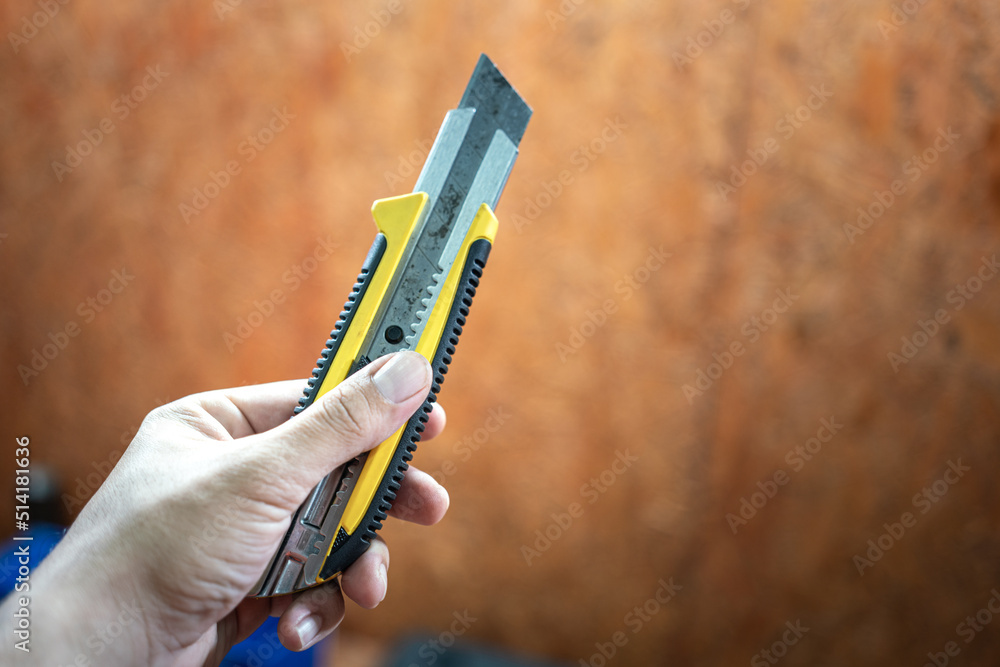 The serviceman is holding a big cutter knife, the utility hand tool ...