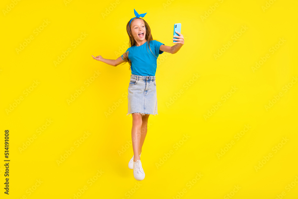 Full size photo of excited small girl jumping hold telephone make ...