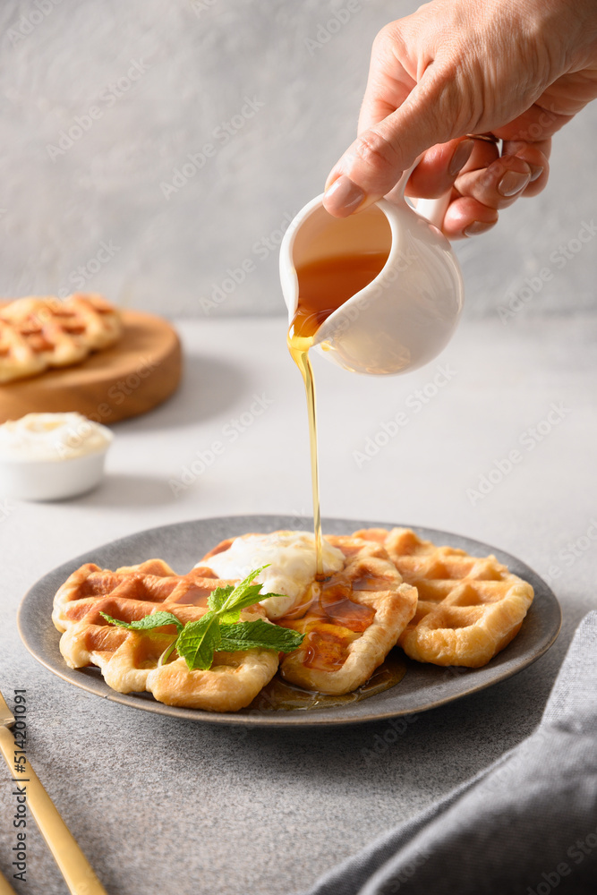 Woman pouring syrup on fresh crispy croffles for tasty breakfast ...