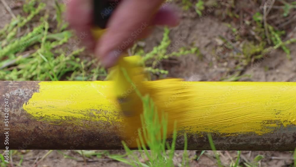 Video Stock Close-up of a brush painting a pipe with yellow paint. The ...