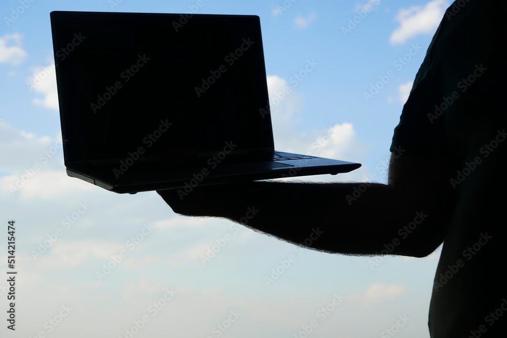 Man holding on hand Laptop. isolated on blue cloudy sky background ...