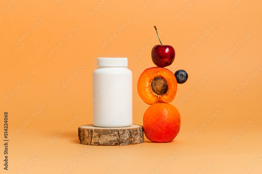 Vitamin bottle of bio supplement with fresh fruits on wooden stand ...