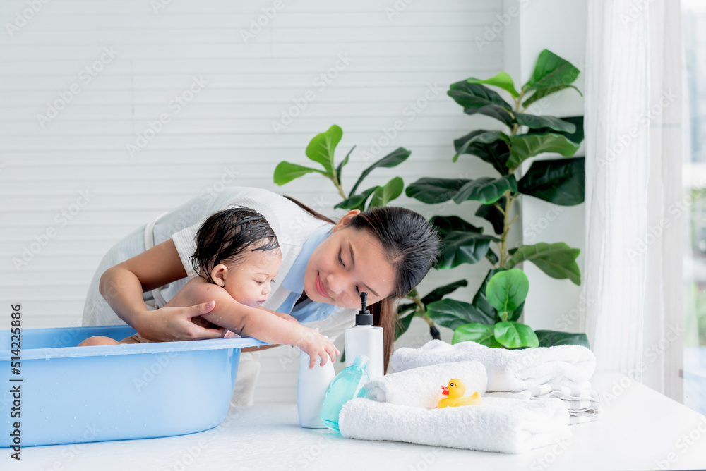 Asian mother Bathing her 7 month old daughter, which the baby smiling ...