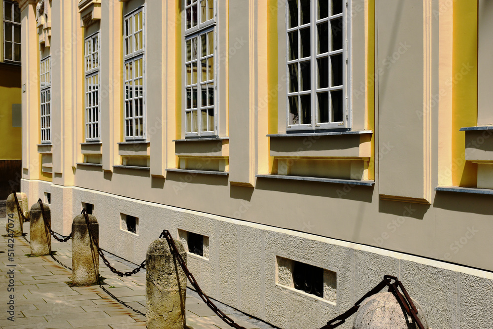 painted white wood windows. yellow stucco elevation. stone bollards ...