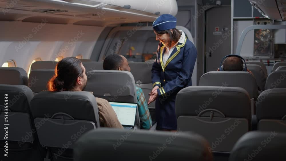 Flight attendant assisting passengers to board on airplane, talking ...