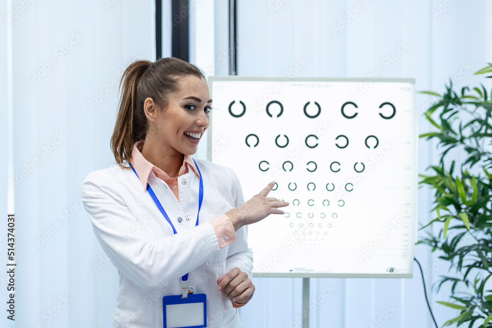 Professional female optician pointing at eye chart, timely diagnosis of ...