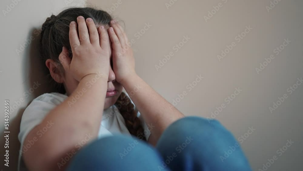 sad girl sitting in the corner crying a covered her face with her hands ...