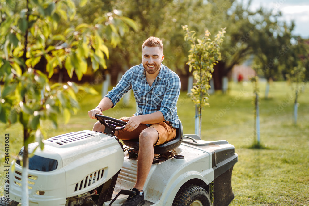 Smiling man - Professional lawn mower with worker cutting the grass in ...