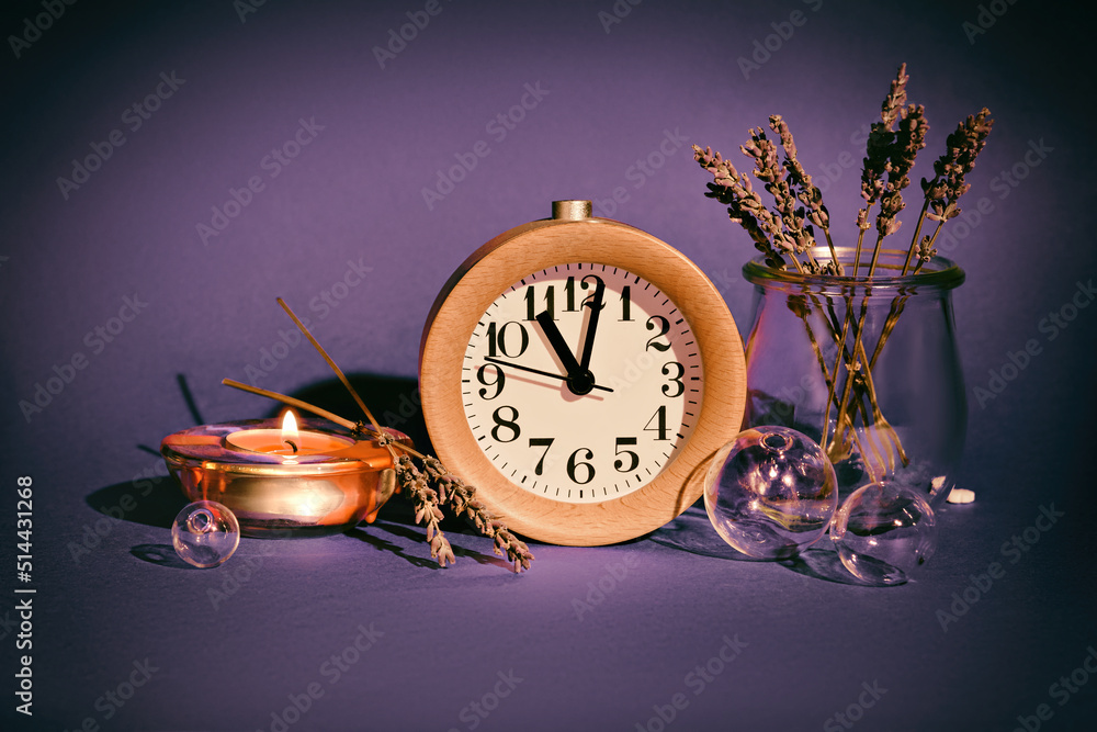 Still life arrangement with wood alarm clock on purple background. Dry ...