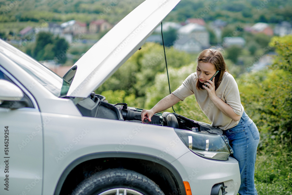 The woman pulls out a probe in her car engine to check the oil level ...