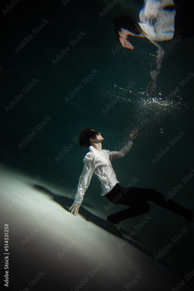 Beautiful underwater shooting, guy in white shirt and pants has fallen ...