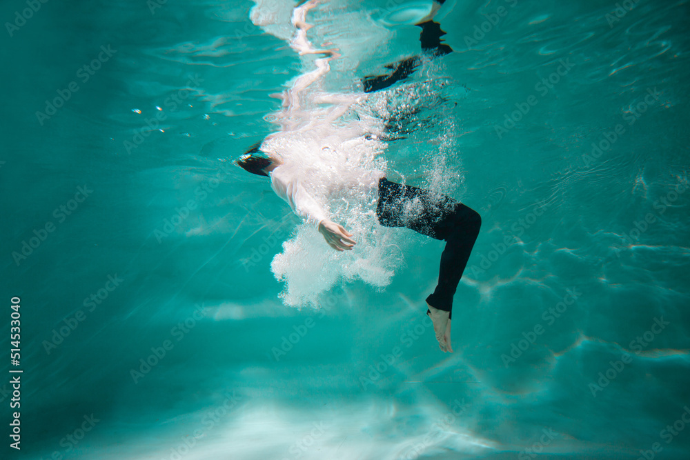 Beautiful underwater shooting, guy in white shirt and pants has fallen ...