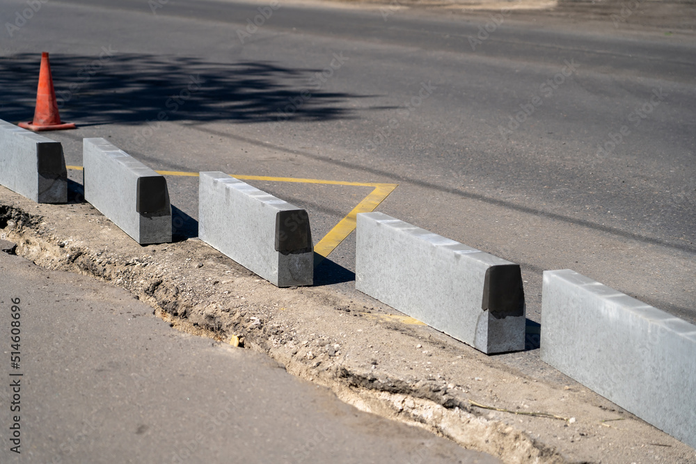 Roadside concrete curb stone with potholed road surface. Road repair ...
