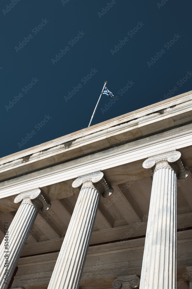 Foto de A greek flag on a pole waving above gigantic columns of a ...