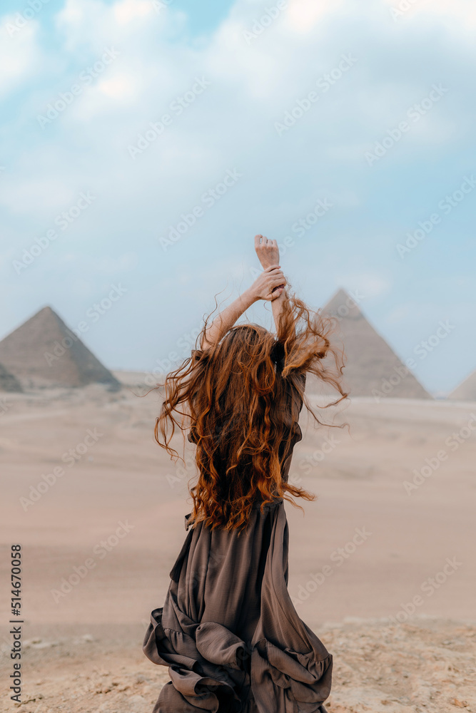 Back view of the young redhead girl with raised hands watching the ...