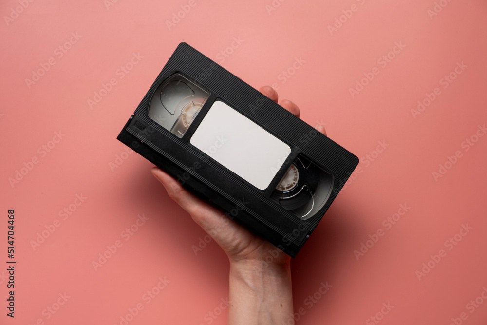 Woman's hand holding old video tape on pink background. VHS video tape ...